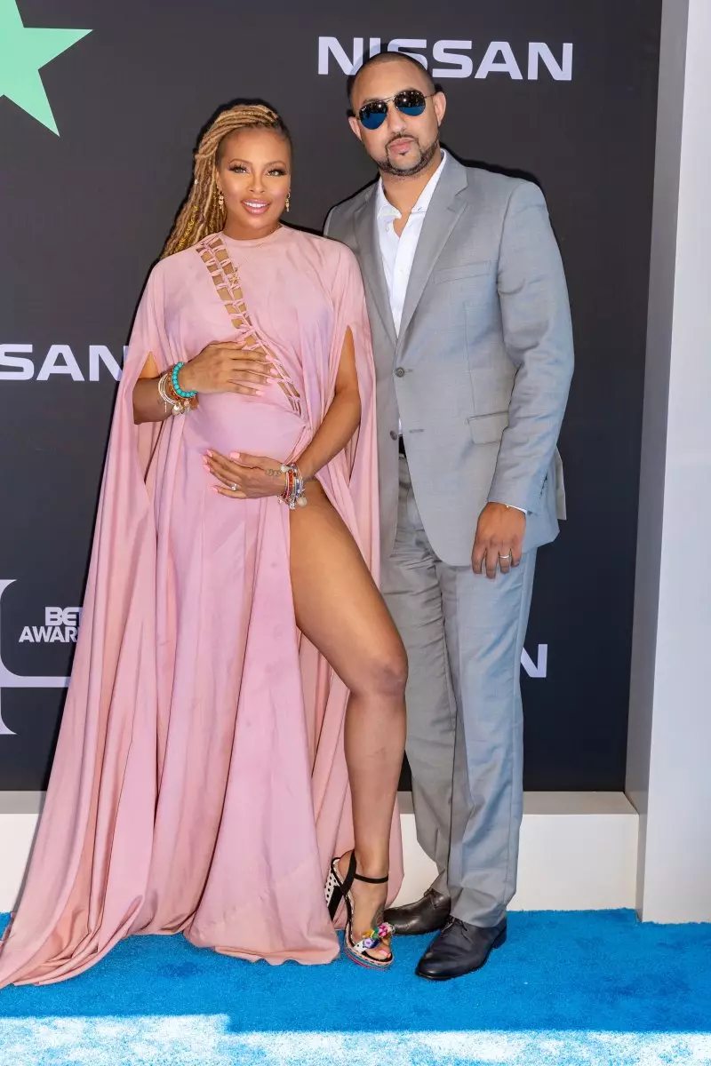 swangere 'rhoa'-stjer eva marcille wikkelet har poppebult yn in ljochtroze flierlange vloeiende jurk, wylst har man michael sterling njonken har posearret yn in wyt shirt mei knooppunt mei in griis pak en in sinnebril by de 2019 BET-prizen