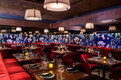 el interior de papi steak cuenta con asientos de terciopelo rojo, mesas de madera noble y un exótico estampado floral en las paredes