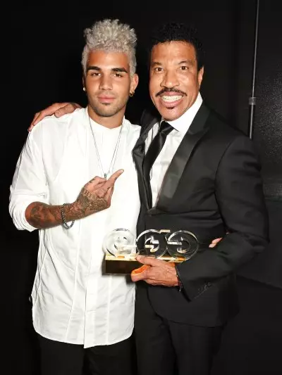 Miles Richie trägt ein weißes Hemd mit blonden Haaren mit Papa Lionel Richie, der einen schwarzen Anzug trägt